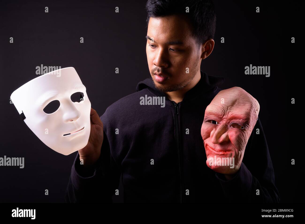 Portrait of young Asian man with hoodie holding two masks Stock Photo ...