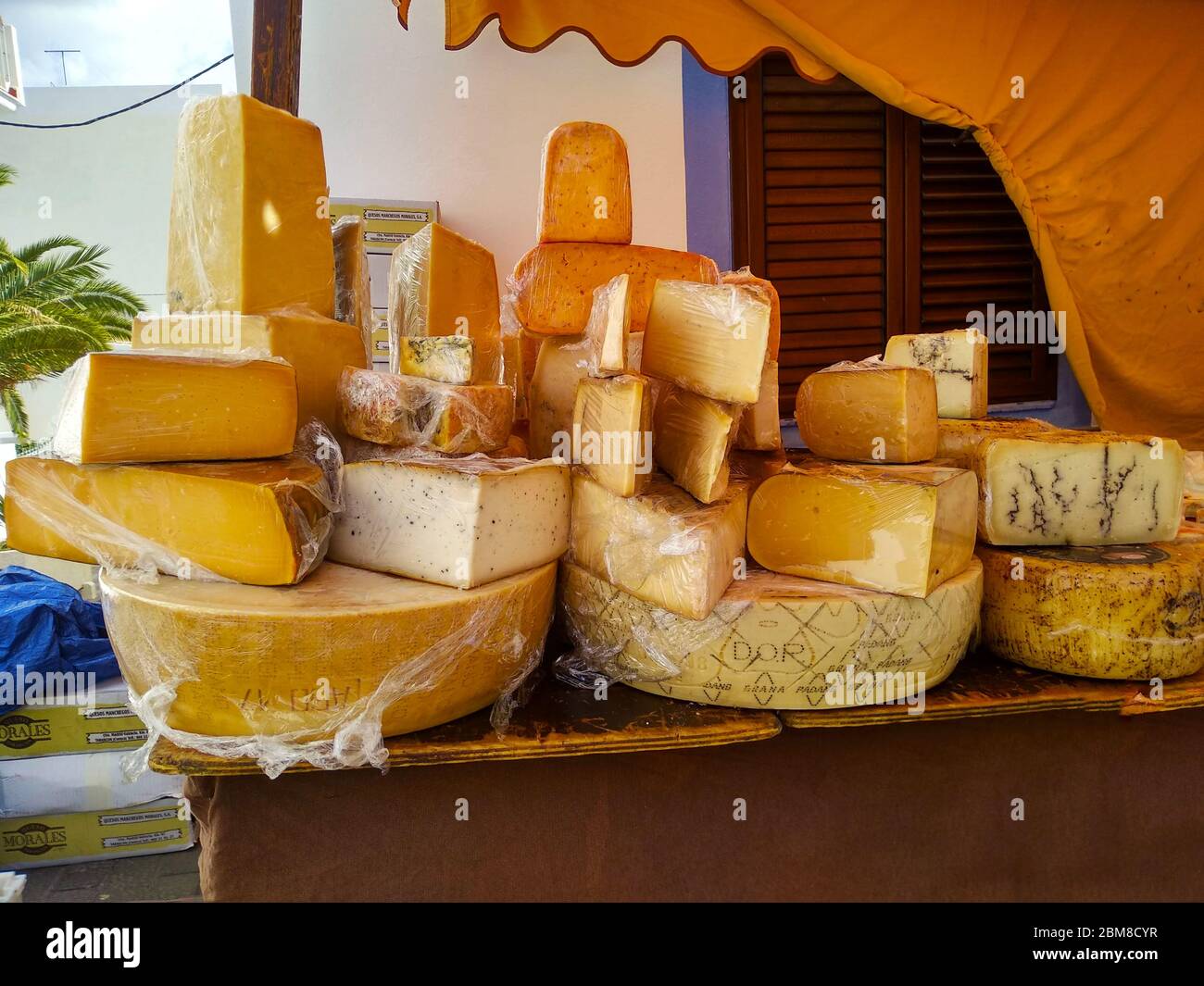 arrangement of fresh and aged yellow cheese shapes at the market in ...