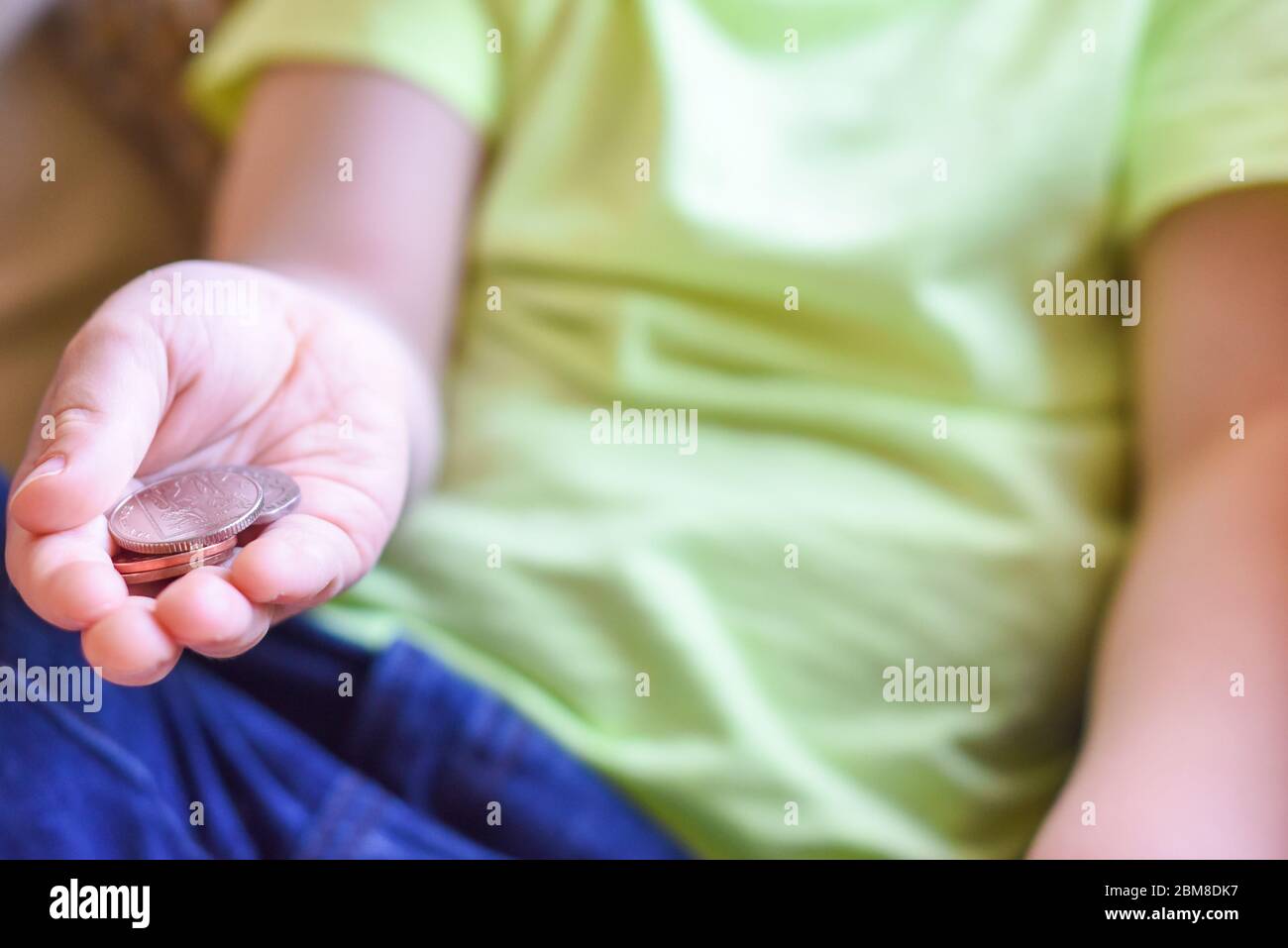 Child holding money in hand cash is UK currency coins Stock Photo - Alamy