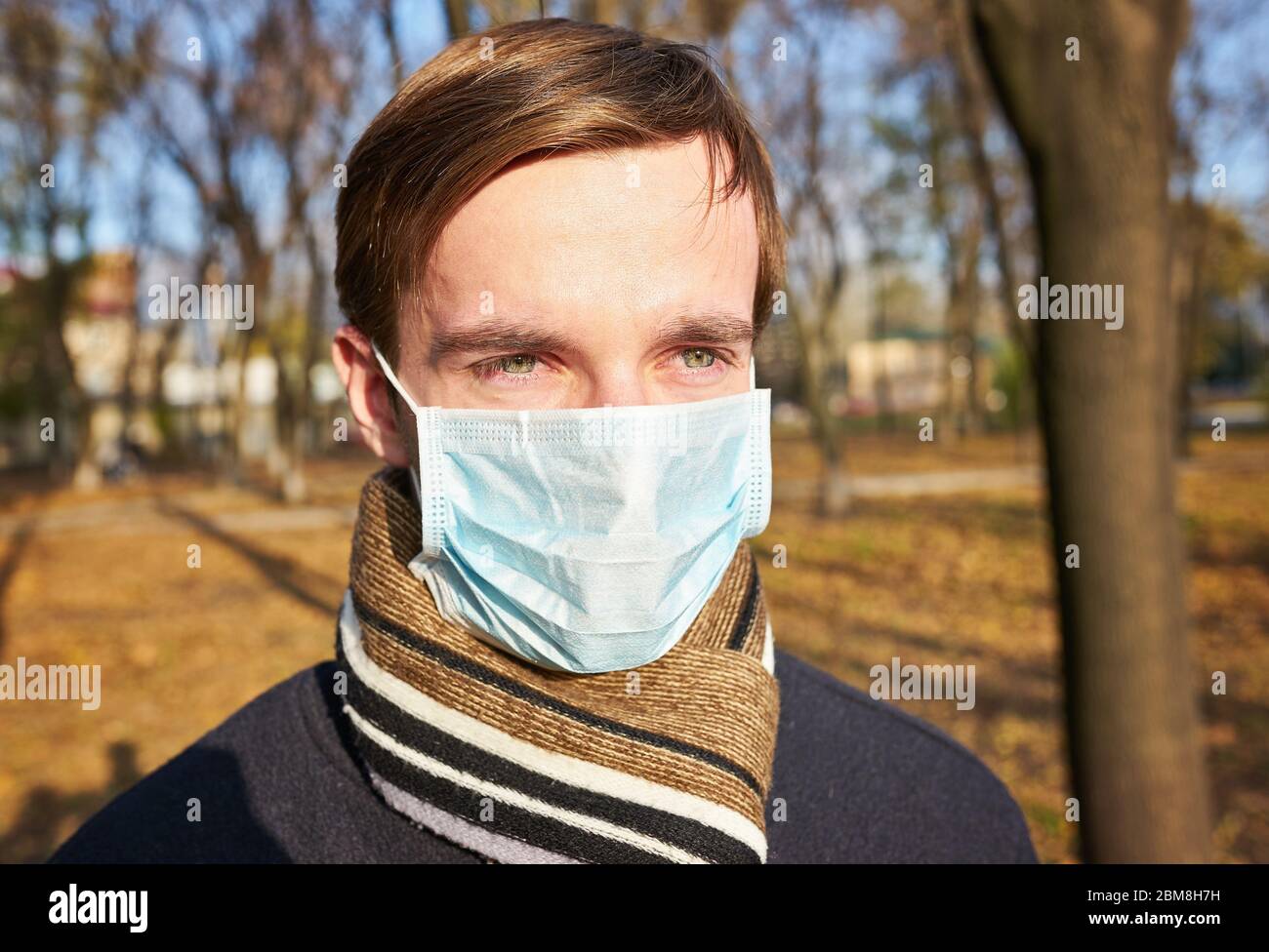 Closeup portrait of a young guy in a disposable medical mask. Pandemic ...
