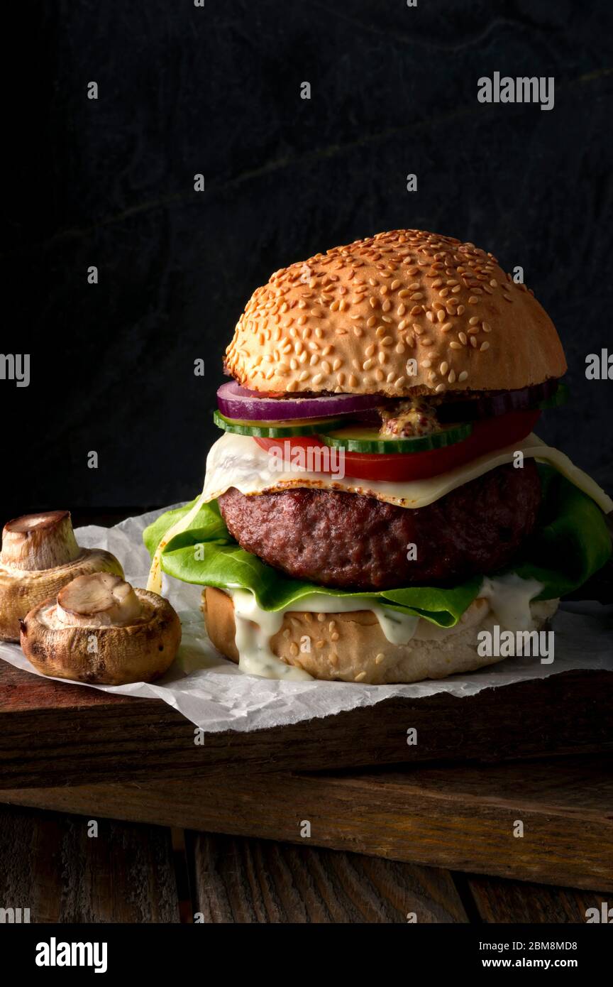 Homemade burger with sesame seed bun, grilled beef, sauce, vegetables ...