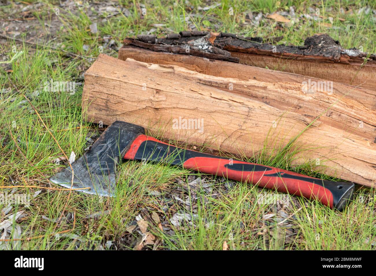 Ax with sharp blade and red and black rubber handle lying on green ...