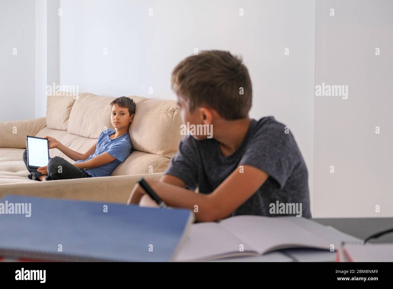 Brothers at home talking about homework tasks. Boy doing homework with ...