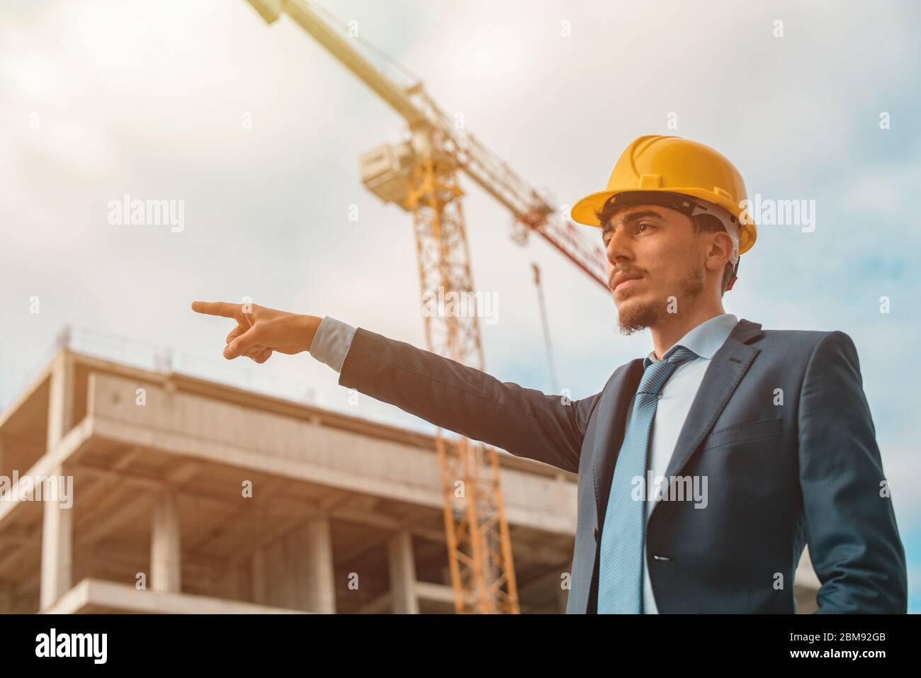 Young construction engineer with yellow helmet crane and construction ...