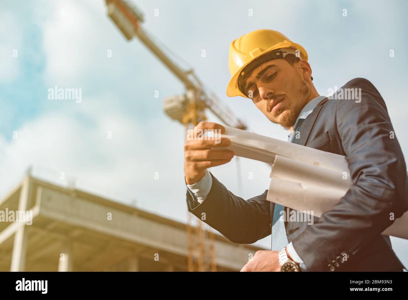 Young construction engineer with yellow helmet crane and construction ...
