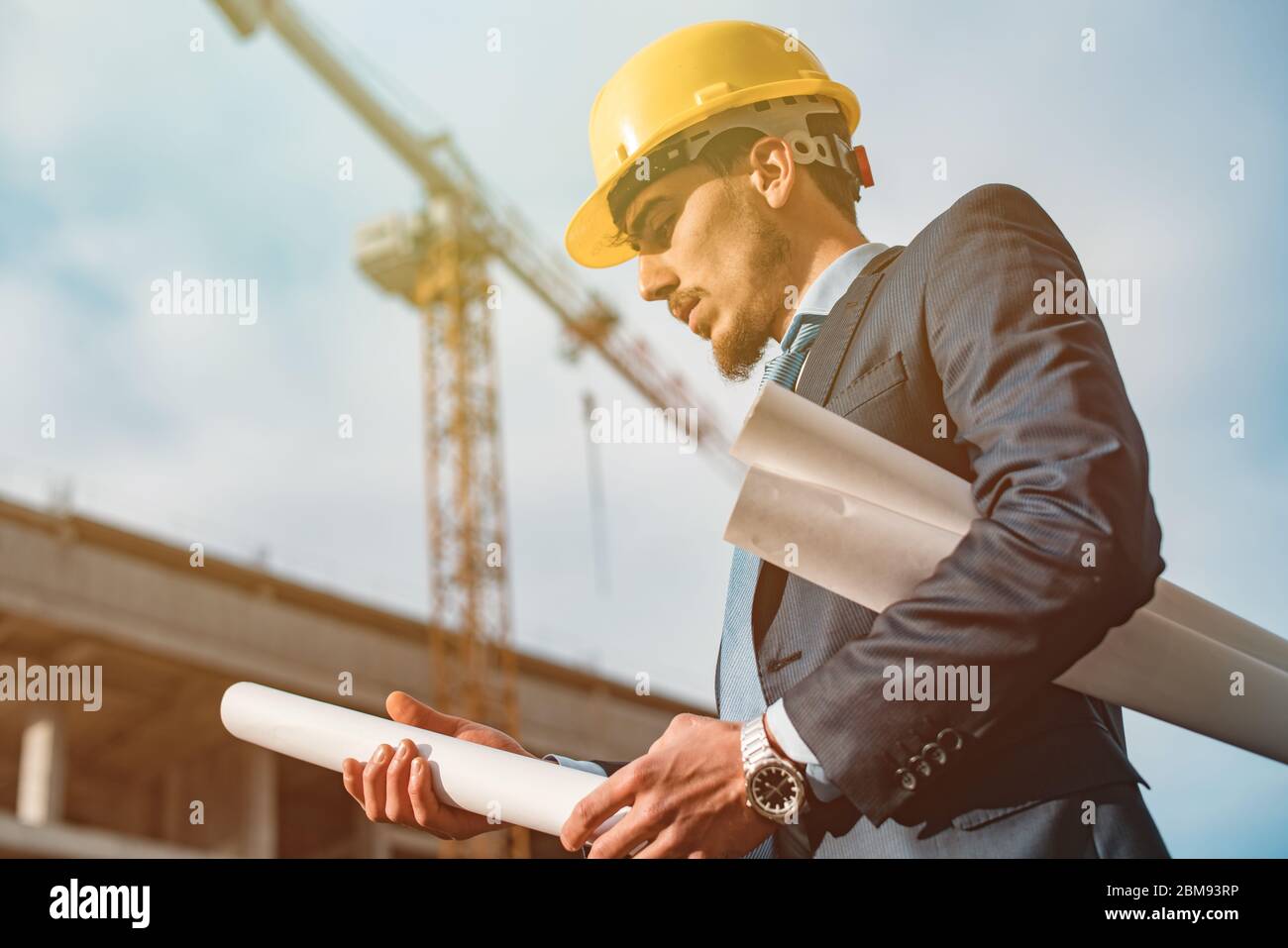 Young construction engineer with yellow helmet crane and construction ...
