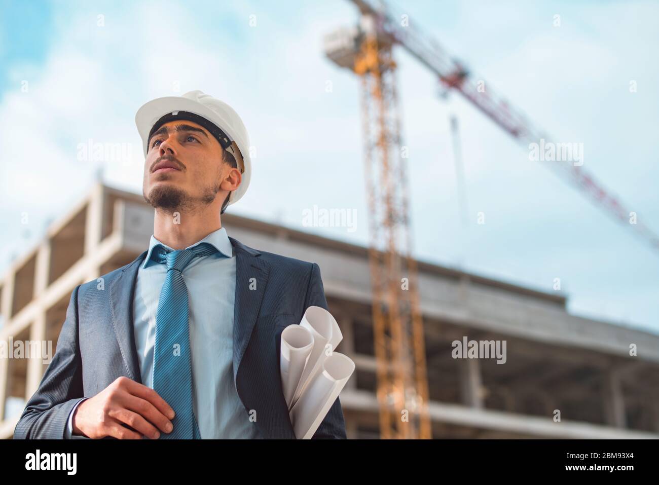 Young construction engineer with yellow helmet crane and construction ...
