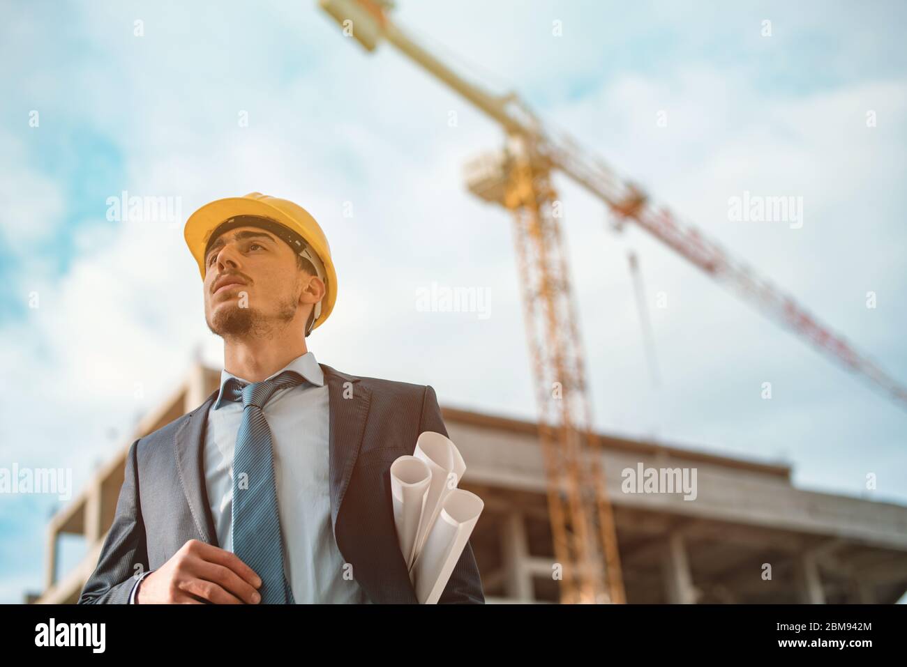 Young construction engineer with yellow helmet crane and construction ...