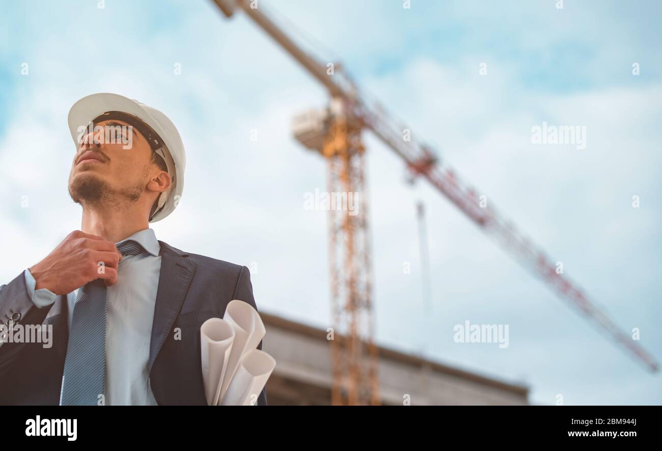 Young construction engineer with yellow helmet crane and construction ...