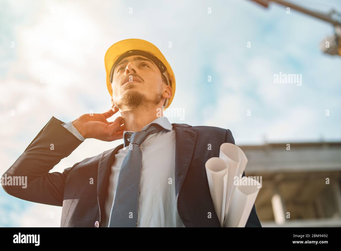 Young construction engineer with yellow helmet crane and construction ...