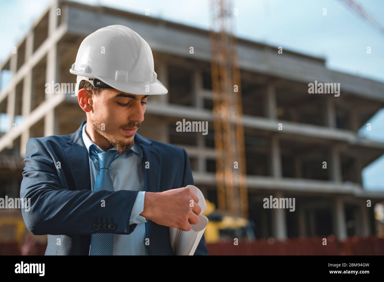 Young construction engineer with yellow helmet crane and construction ...