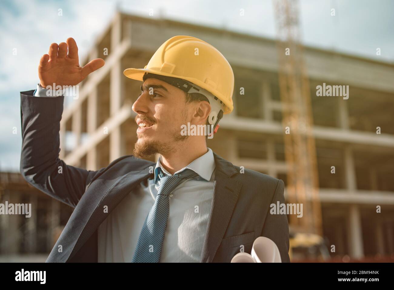 Young construction engineer with yellow helmet crane and construction ...