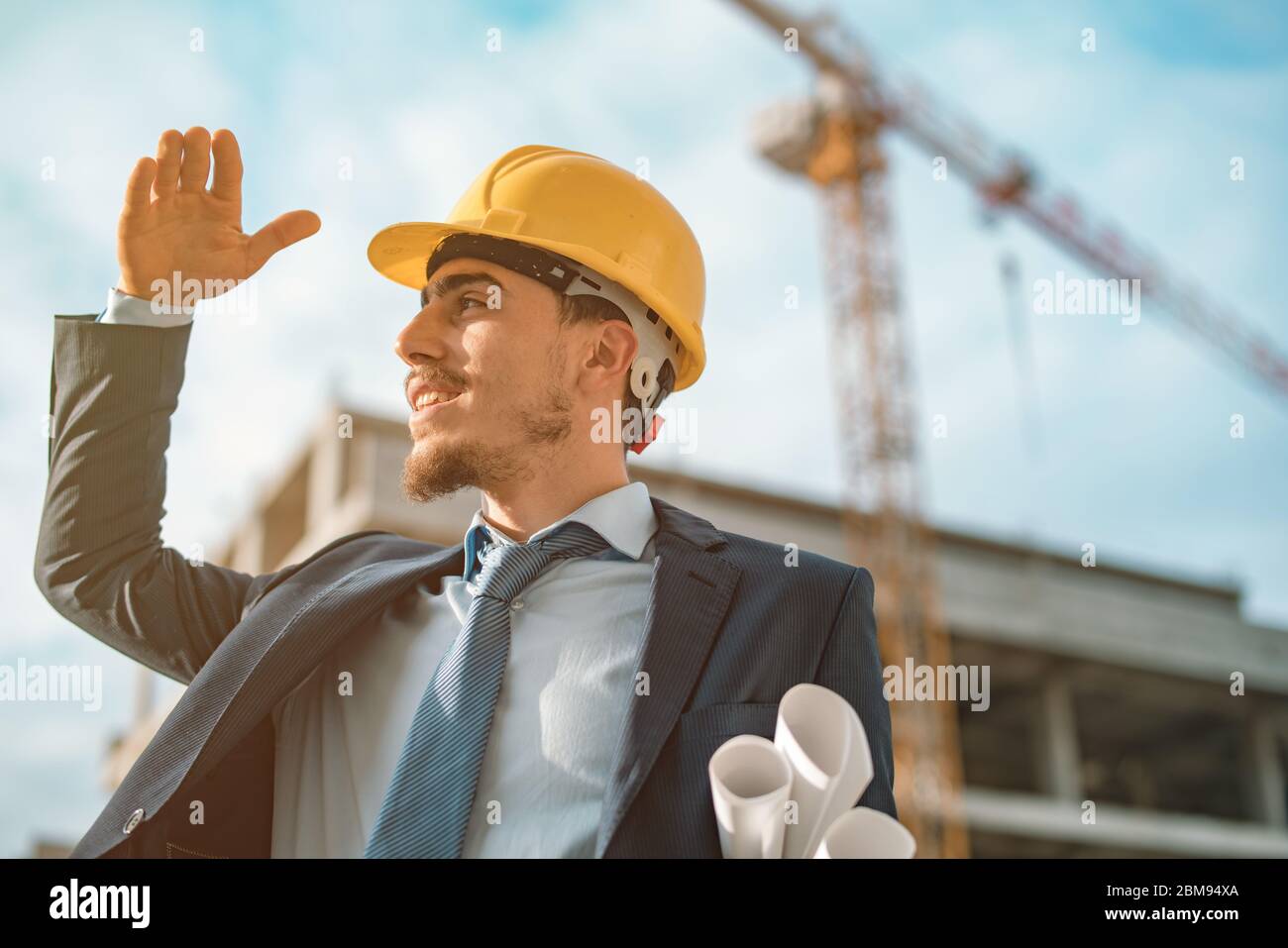 Young construction engineer with yellow helmet crane and construction ...