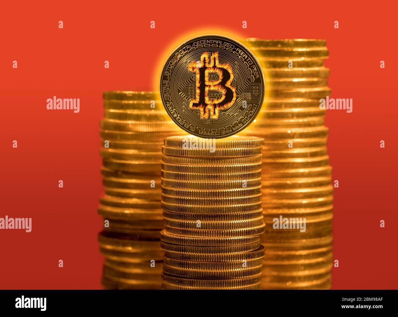 Single bitcoin on stack of golden coins and flame effect to show the ...