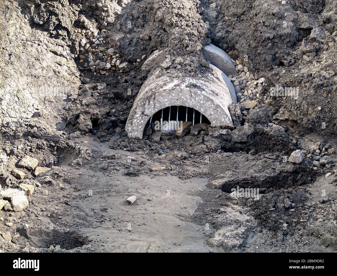 Erosion soil runoff covering a storm water intake culvert with metal ...