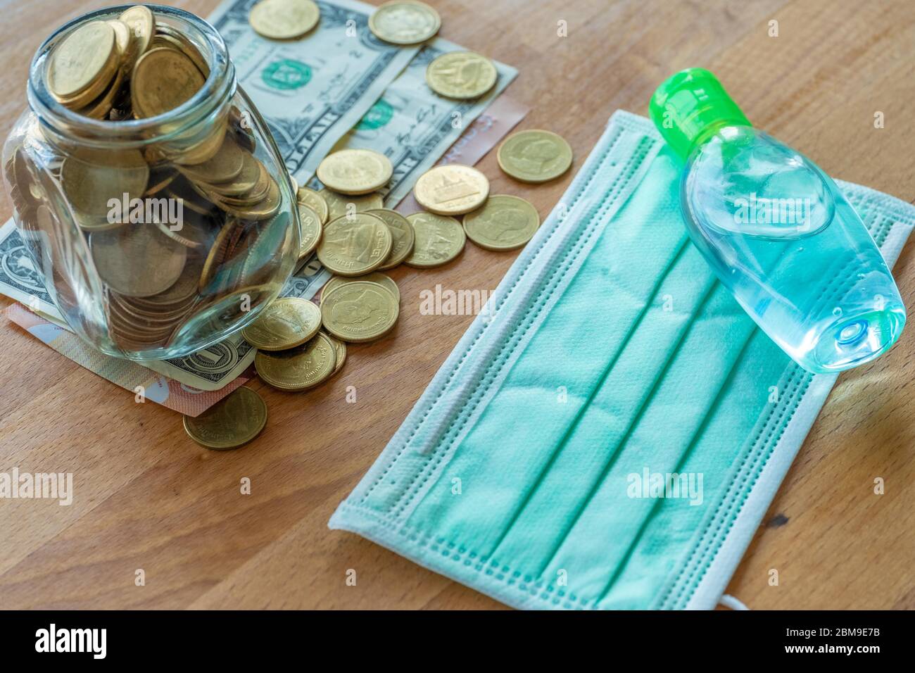 Money on the table such as coins and dollar bill beside face mask and ...