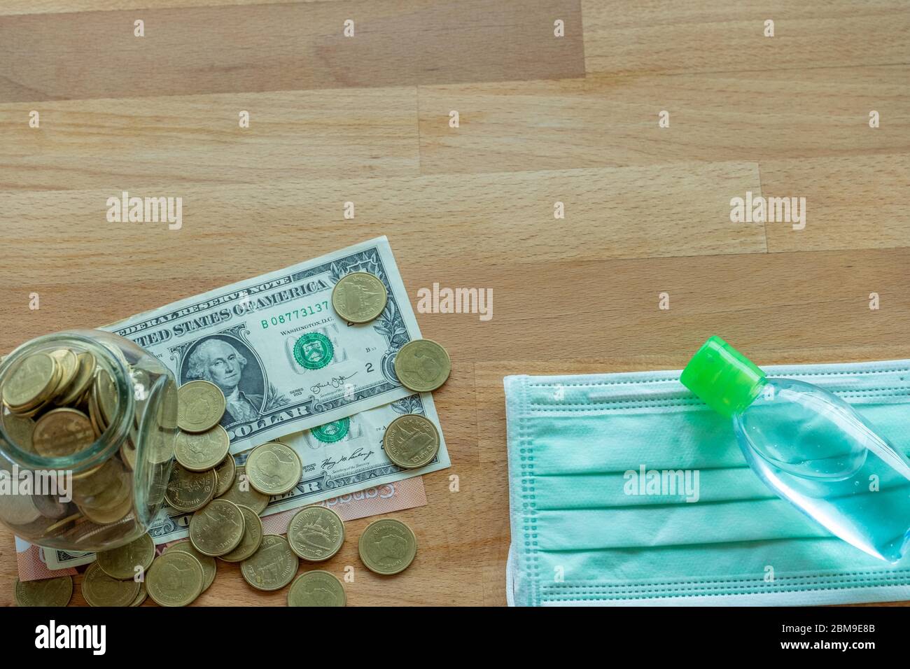 Money on the table such as coins and dollar bill beside face mask and ...