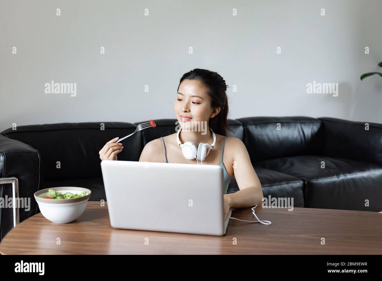 A young Asian woman using a computer in the living room Stock Photo - Alamy
