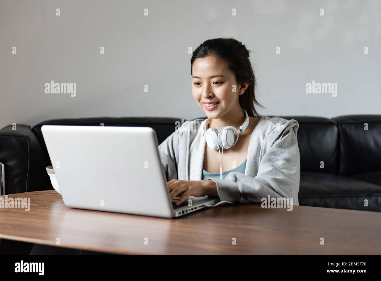 A young Asian woman using a computer in the living room Stock Photo - Alamy