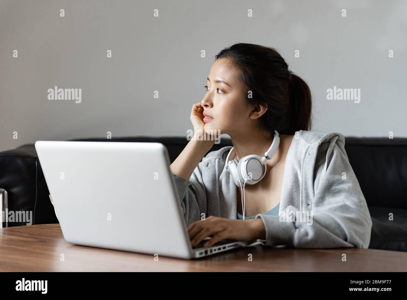 A young Asian woman using a computer in the living room Stock Photo - Alamy