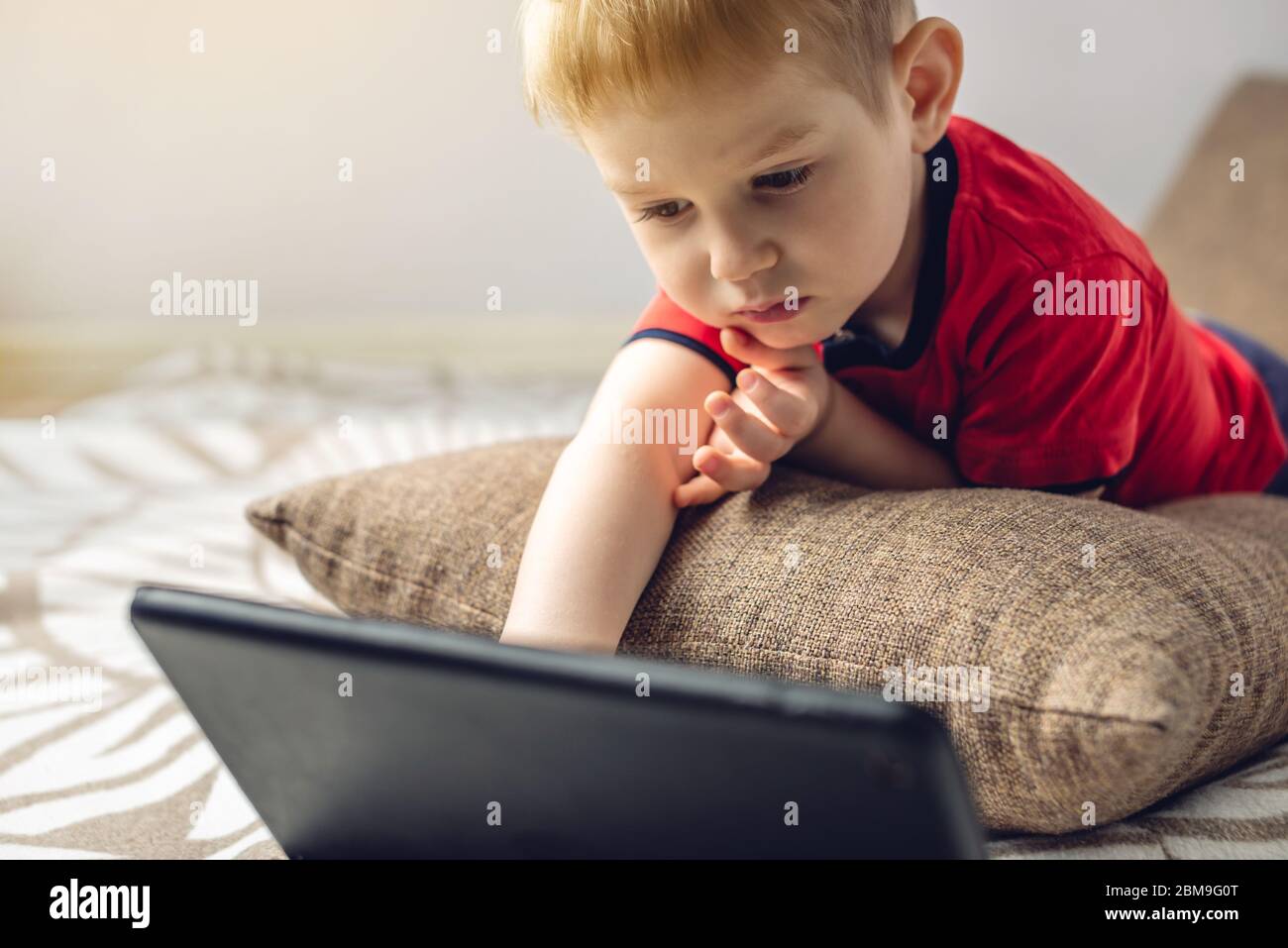 A preschool toddler child watches cartoons on a tablet on the internet ...