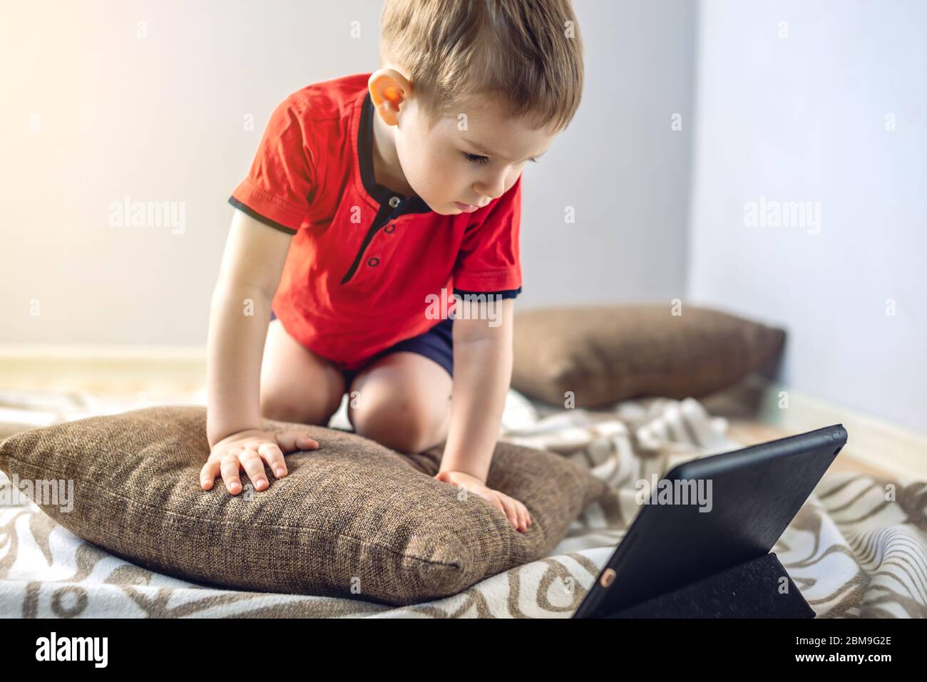 A preschool toddler child watches cartoons on a tablet on the internet ...