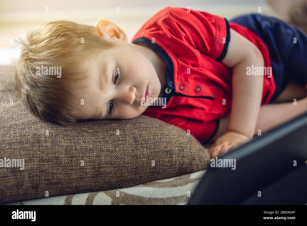 A preschool toddler child watches cartoons on a tablet on the internet ...