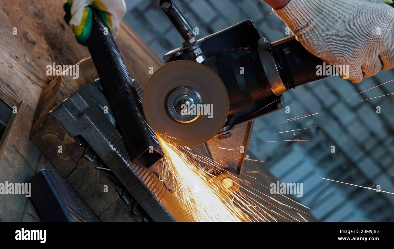 Man worker grinding the seams of an iron frame in the industrial ...