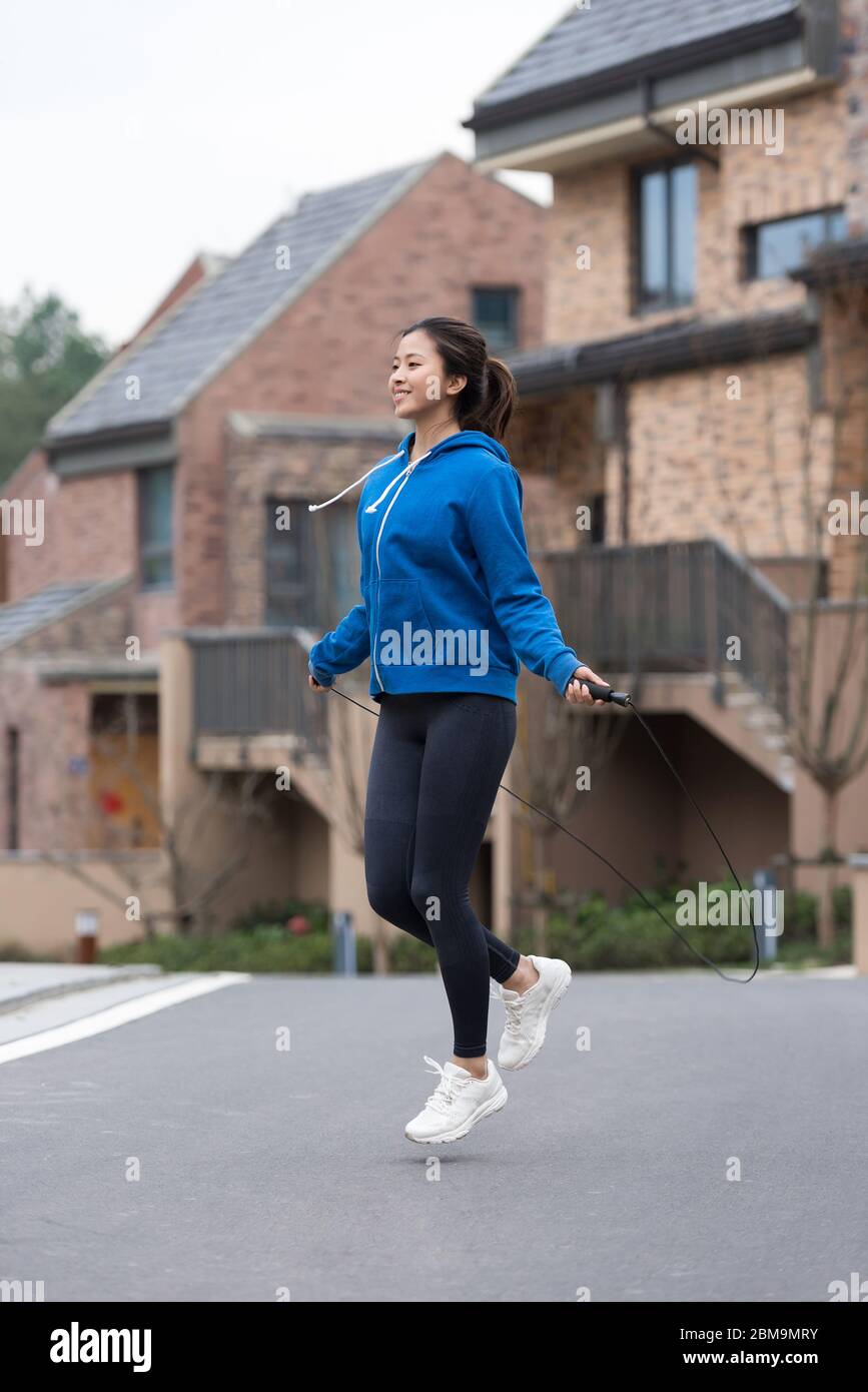 A young Asian woman skipping rope in the city Stock Photo - Alamy