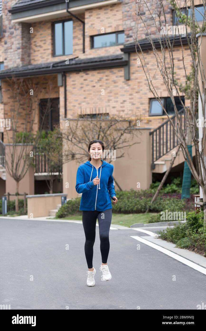 A young Asian woman jogging in the community Stock Photo - Alamy