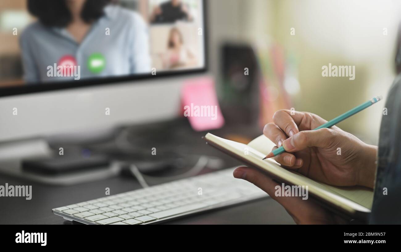 Closeup man taking note and sitting in front his computer monitor while ...