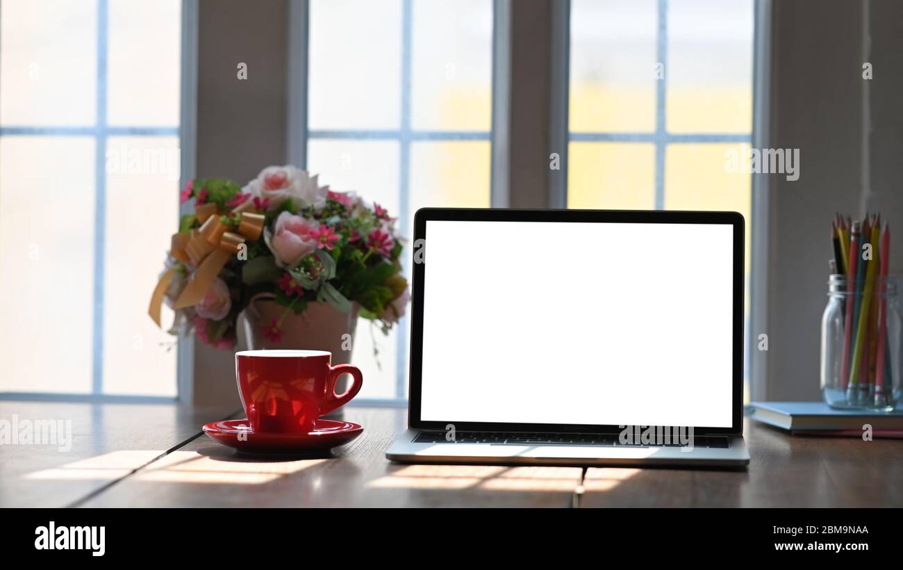 Mockup laptop computer putting on working desk with bunch of flowers ...