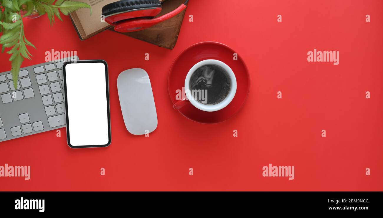 Red office desl coffee cup putting with wireless keyboard, mouse, plant ...