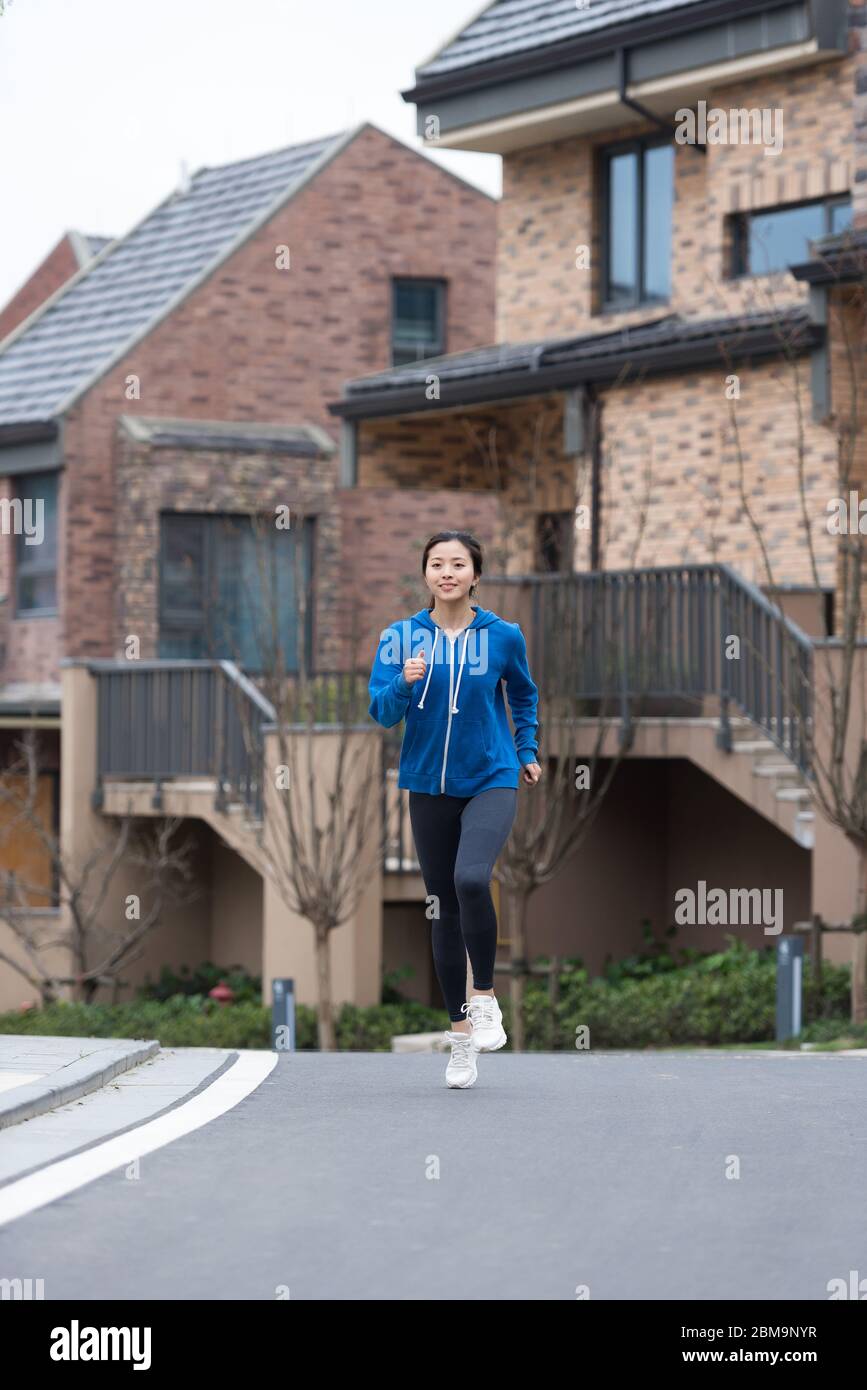 A young Asian woman jogging in the community Stock Photo - Alamy