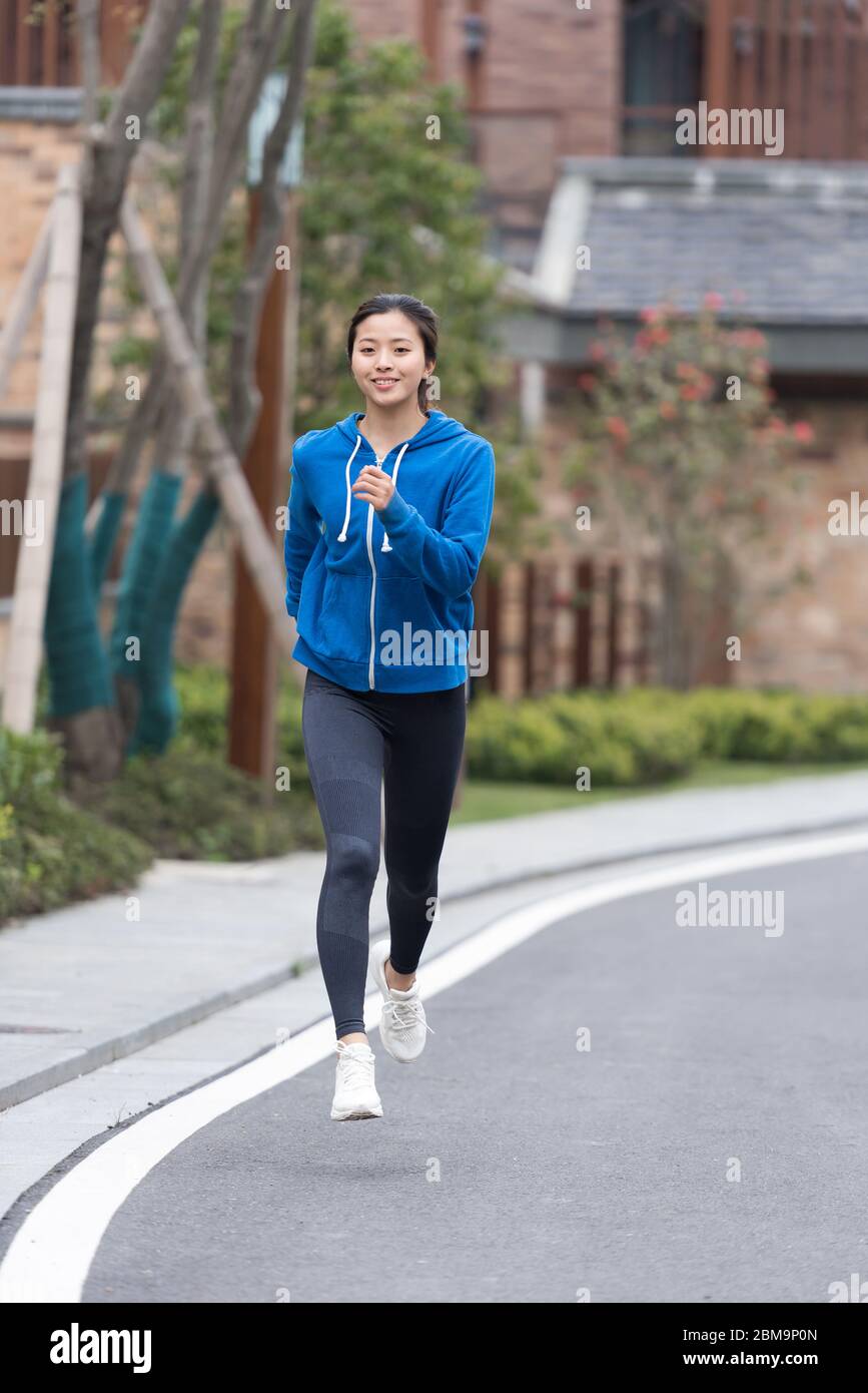 A young Asian woman jogging in the community Stock Photo - Alamy