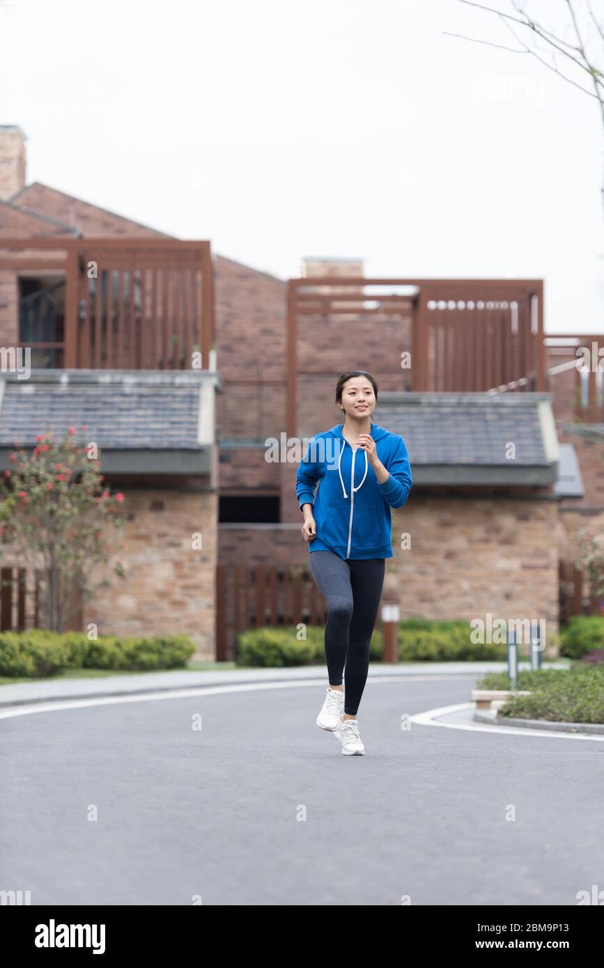 A young Asian woman jogging in the community Stock Photo - Alamy