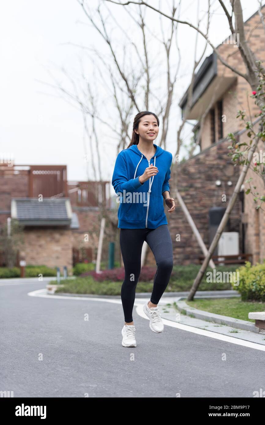 A young Asian woman jogging in the community Stock Photo - Alamy