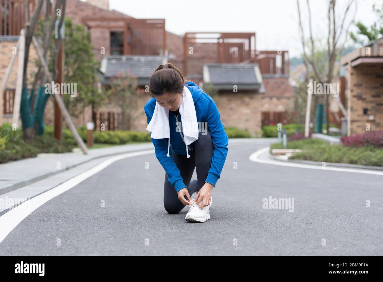 A young Asian woman squatting to tie shoelaces Stock Photo - Alamy
