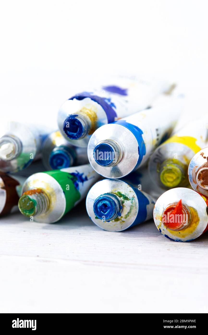 Artist oil paint tubes in various colours on white wood. Art and craft ...