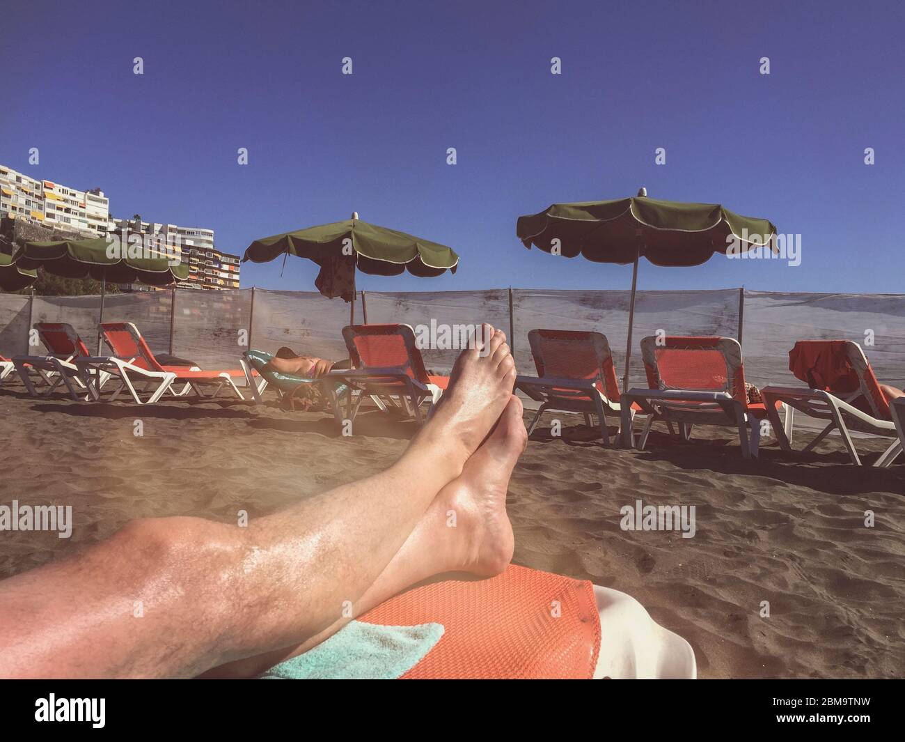 Male legs tanning on a deckchair on the beach Stock Photo - Alamy