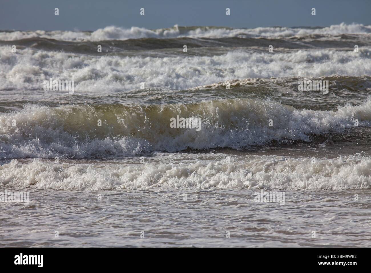 Waves of the north sea with white spindrift in front of a blue sky ...