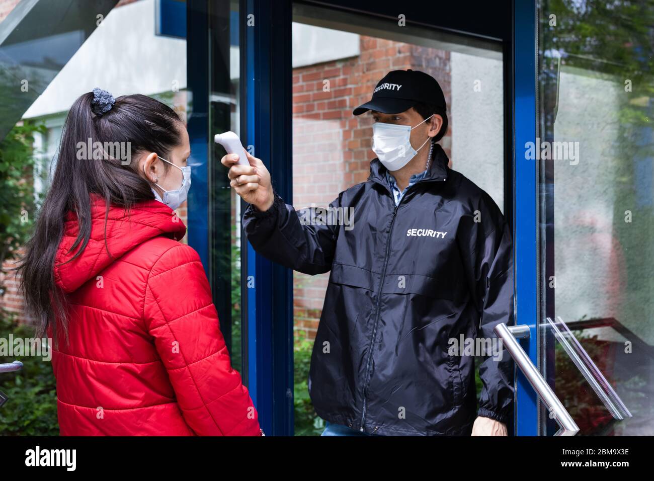 Security Guard Checking Temperature At Building Entrance Stock Photo ...