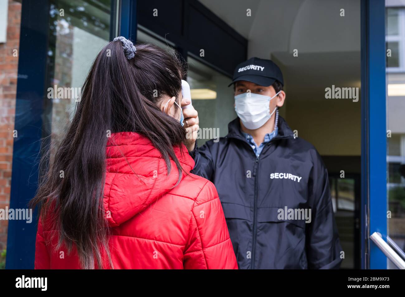 Security Guard Checking Temperature At Building Entrance Stock Photo ...