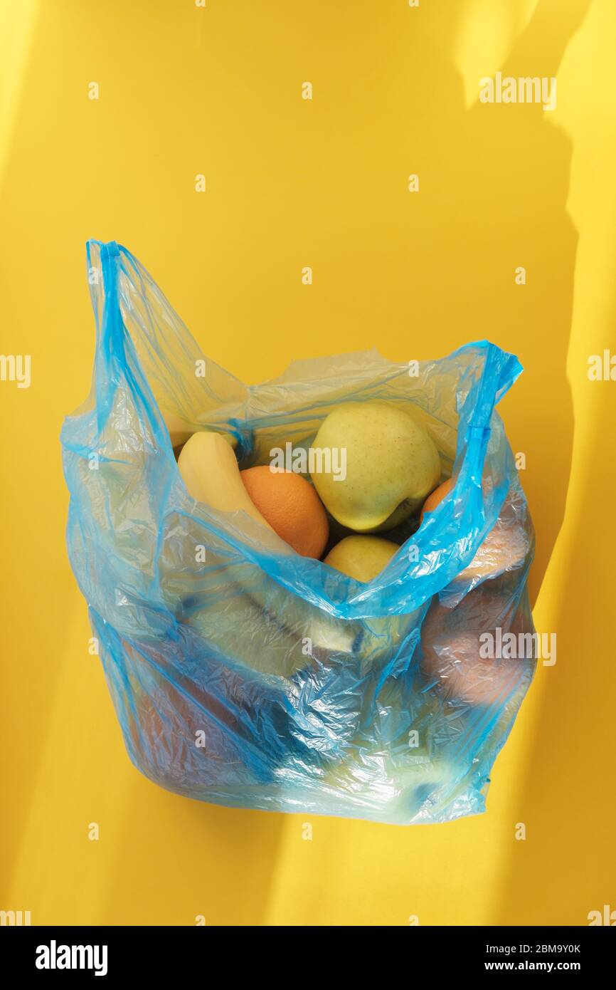 Oranges, Bananas, Apples, Avocados lie in a cellophane plastic blue bag ...