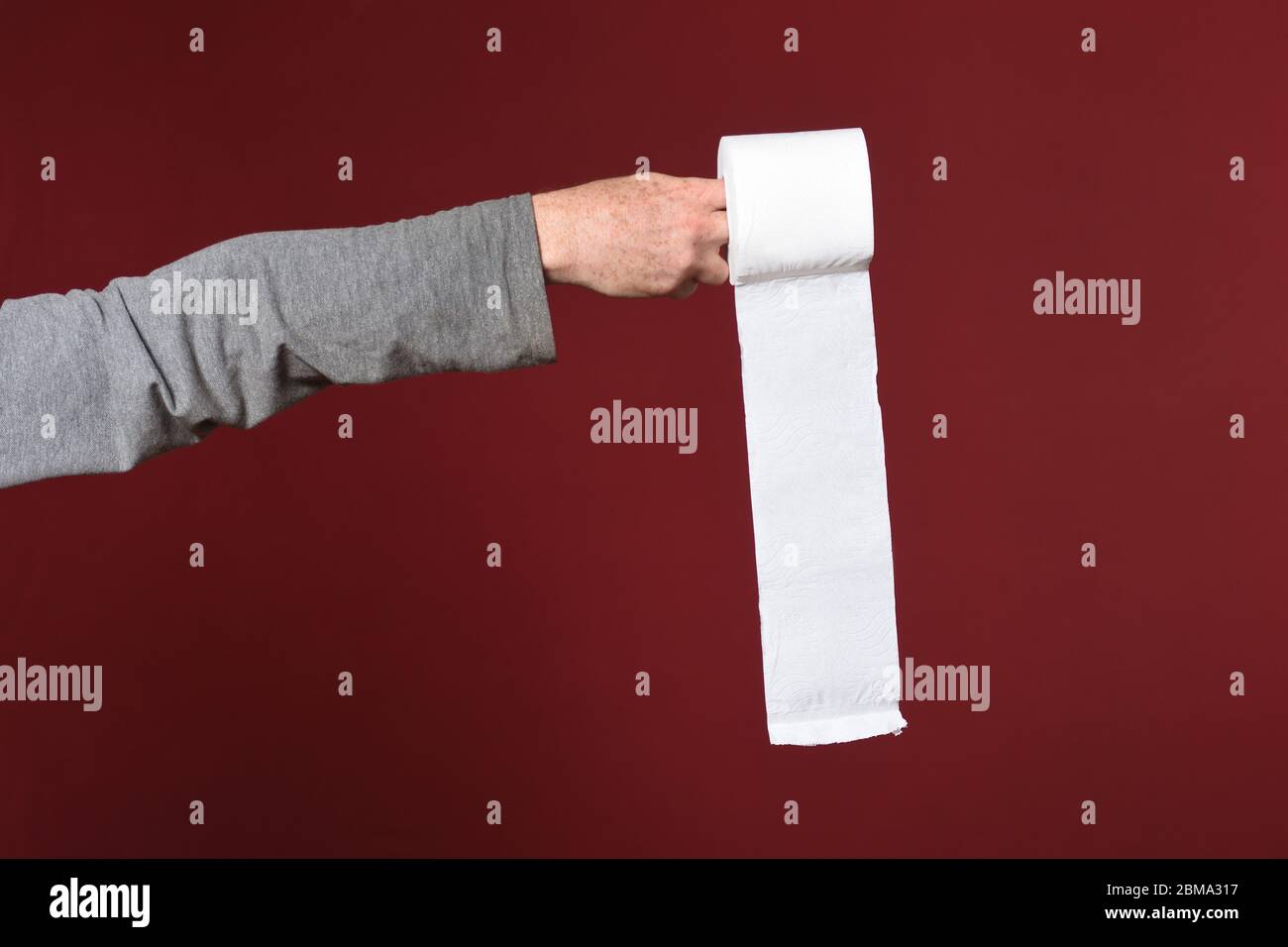 hand holding toilet paper on red background Stock Photo - Alamy