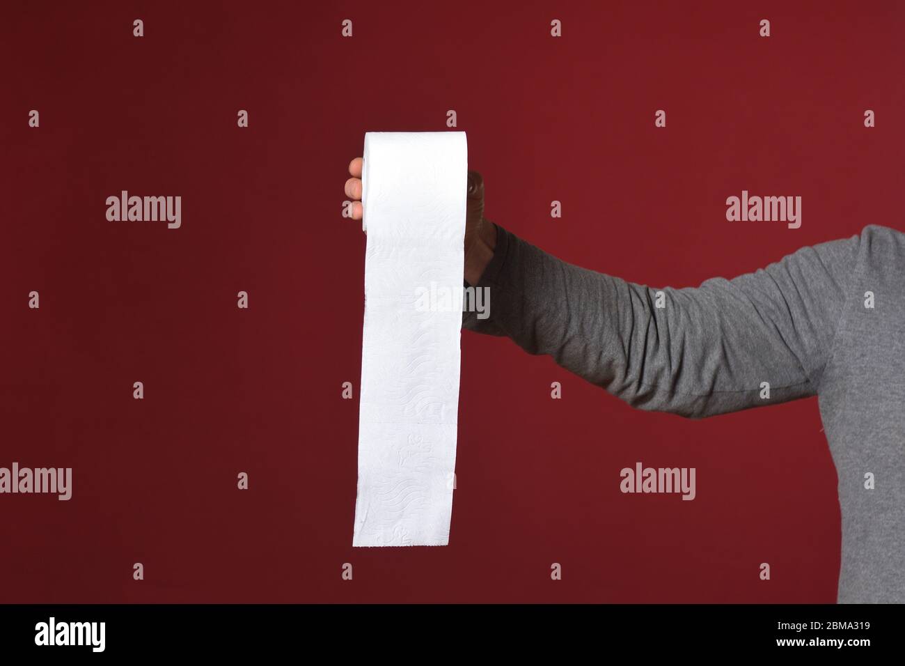 hand holding toilet paper on red background Stock Photo - Alamy