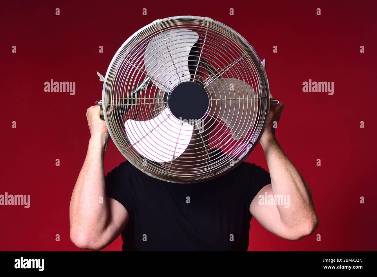 man holding a fan in front of his face on red background Stock Photo ...