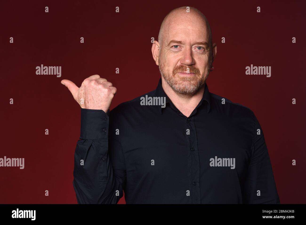 man pointing thumb on red background Stock Photo - Alamy