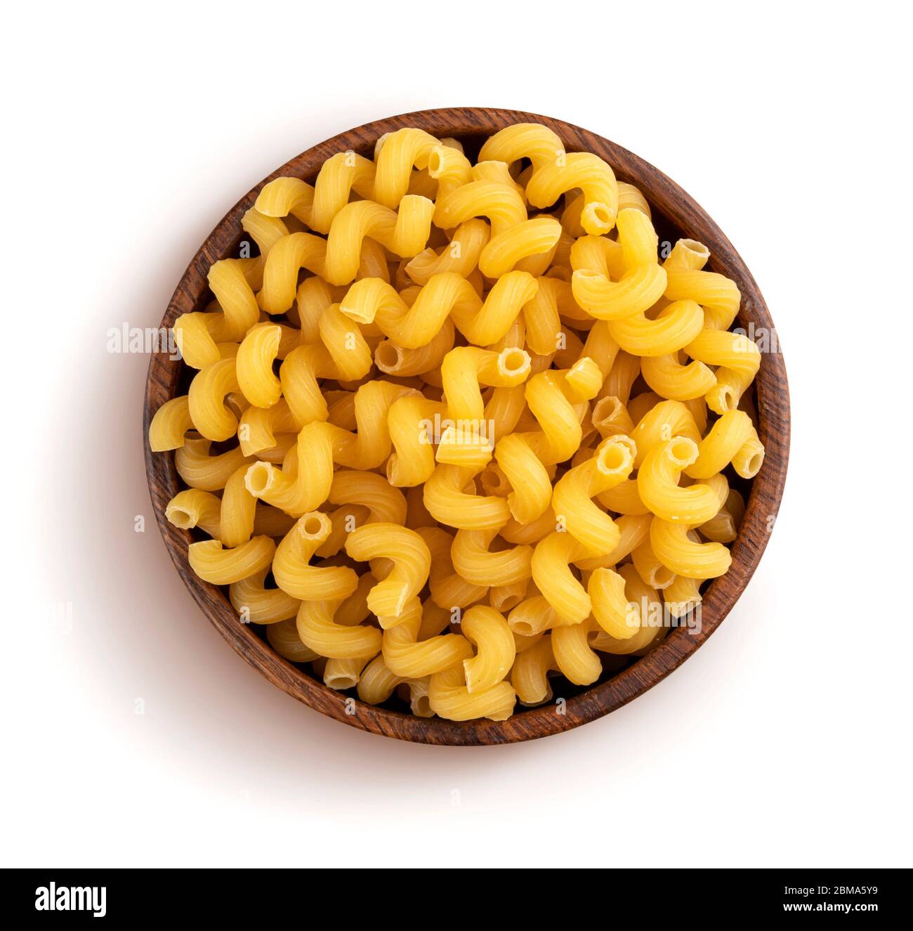 Cellentani pasta in wooden bowl isolated on white background, top view ...