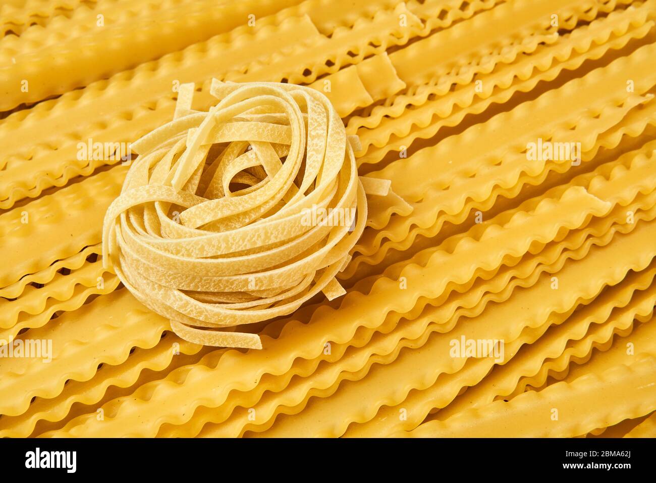 dry pasta tagliatelle and mafaldini warm background Stock Photo - Alamy